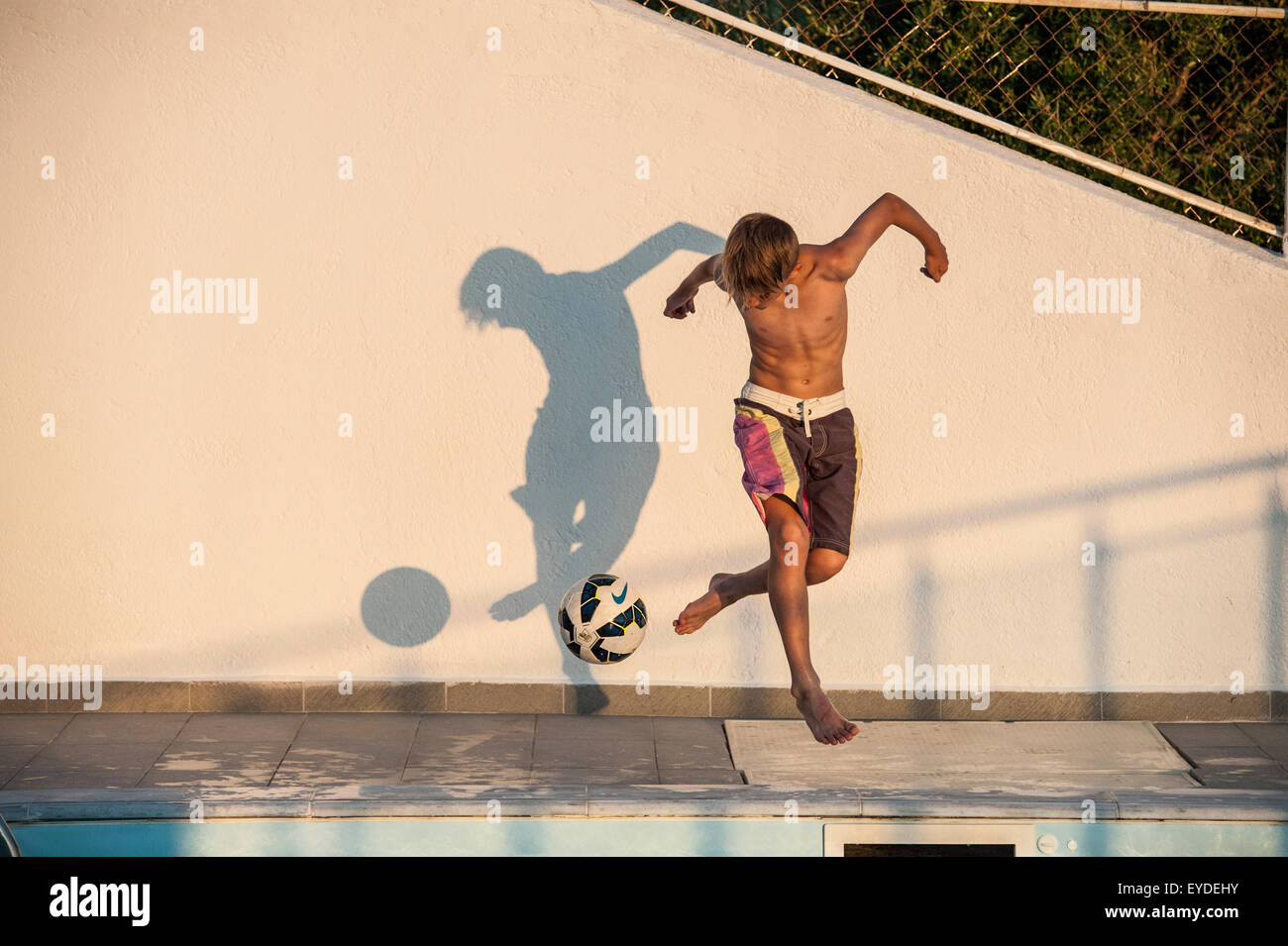 A boy playing football on holiday by a swimming pool Stock Photo - Alamy