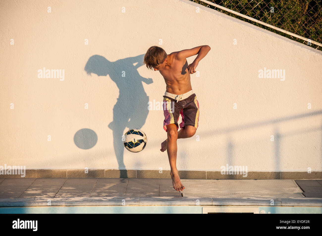 A boy playing football on holiday by a swimming pool Stock Photo - Alamy