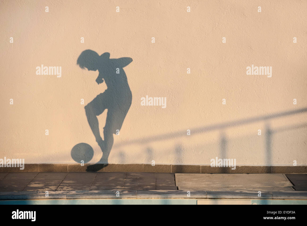 A boy playing football on holiday by a swimming pool Stock Photo - Alamy