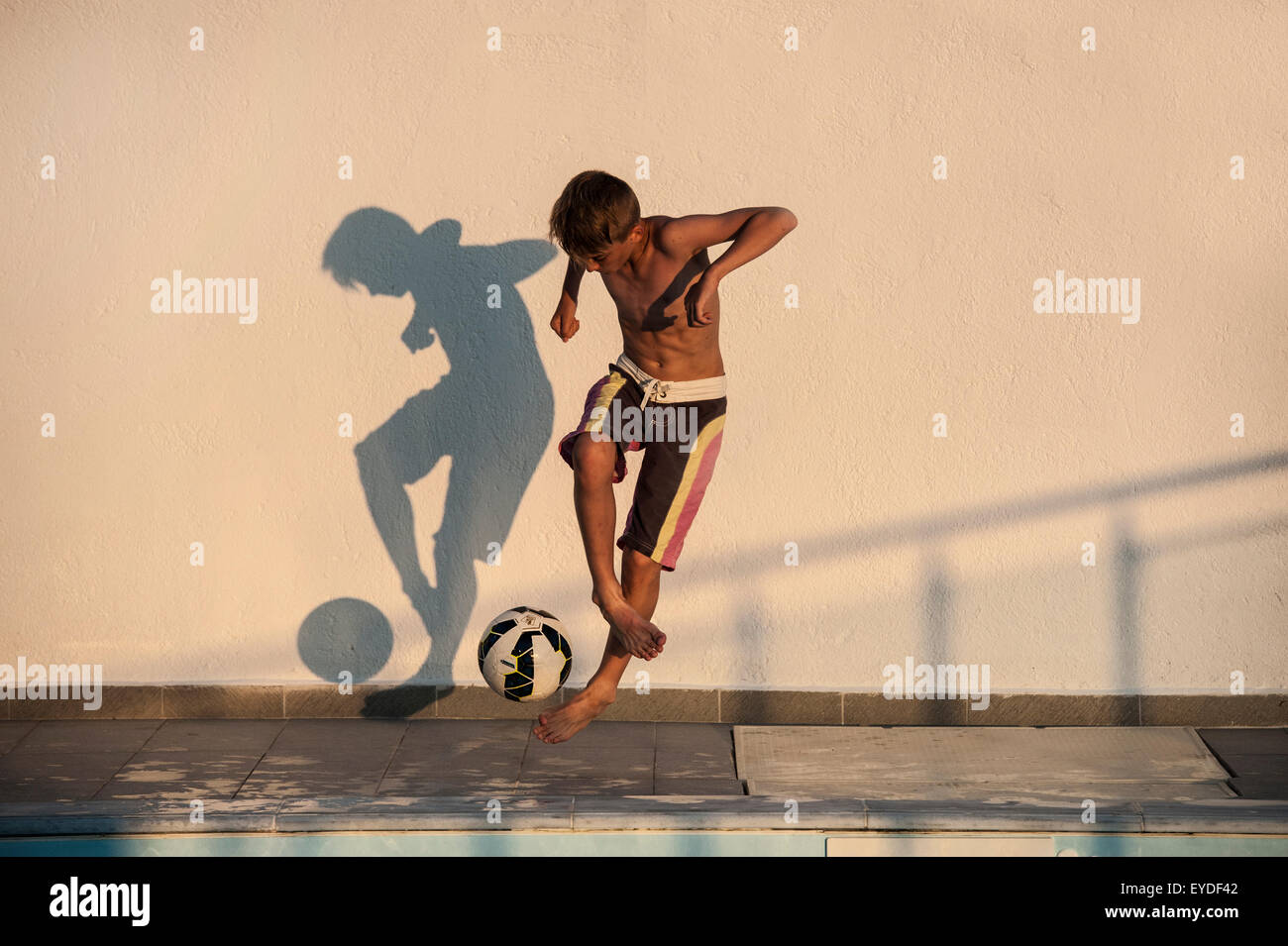 A boy playing football on holiday by a swimming pool Stock Photo - Alamy