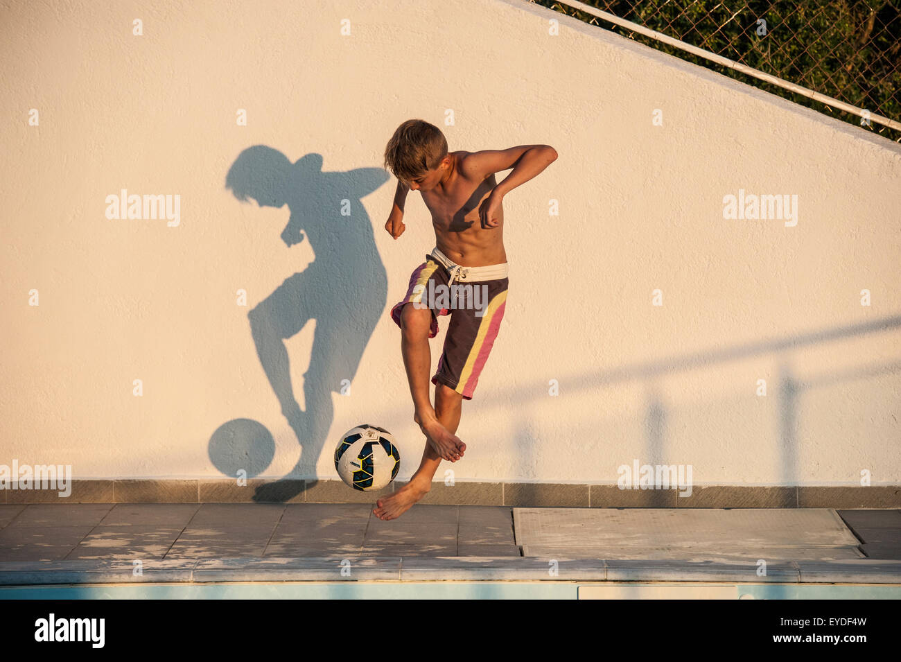 A boy playing football on holiday by a swimming pool Stock Photo - Alamy
