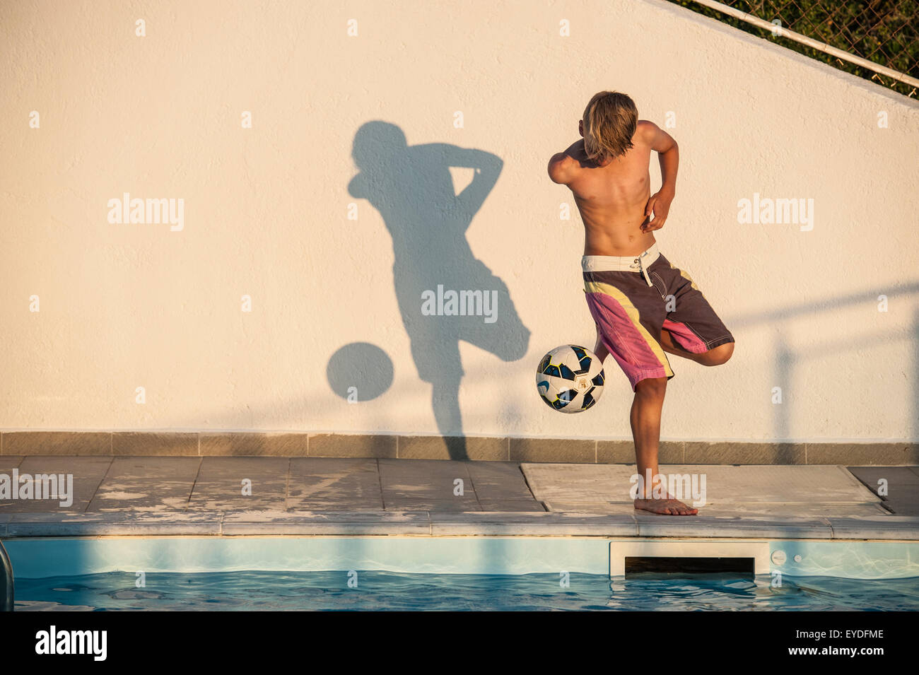 A boy playing football on holiday by a swimming pool Stock Photo - Alamy