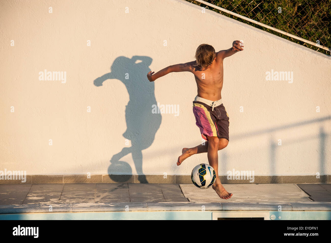 A boy playing football on holiday by a swimming pool Stock Photo - Alamy