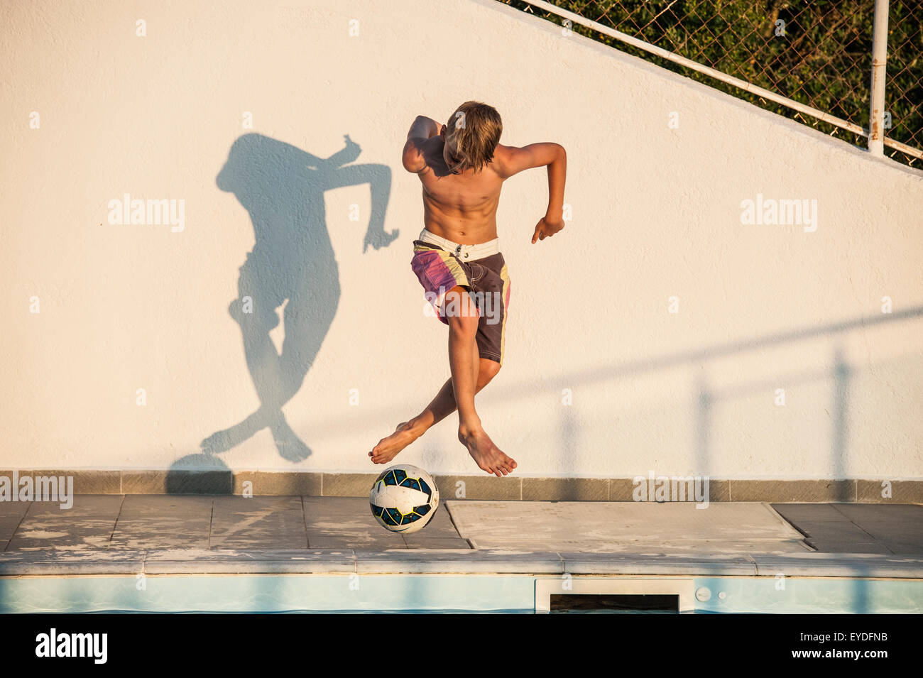A boy playing football on holiday by a swimming pool Stock Photo - Alamy