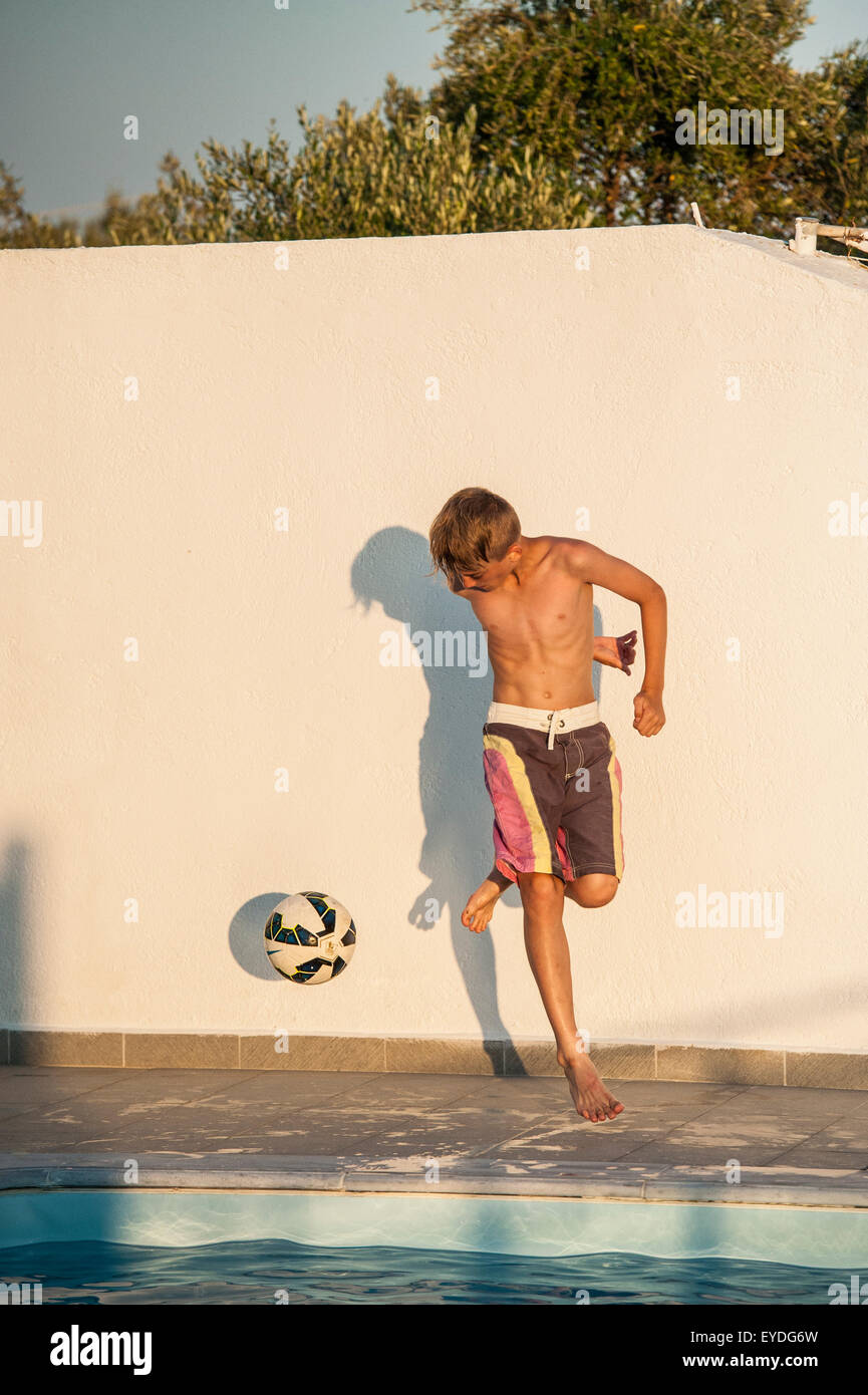 A boy playing football on holiday by a swimming pool Stock Photo - Alamy