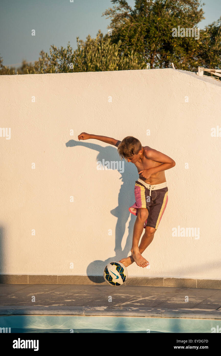 A boy playing football on holiday by a swimming pool Stock Photo - Alamy