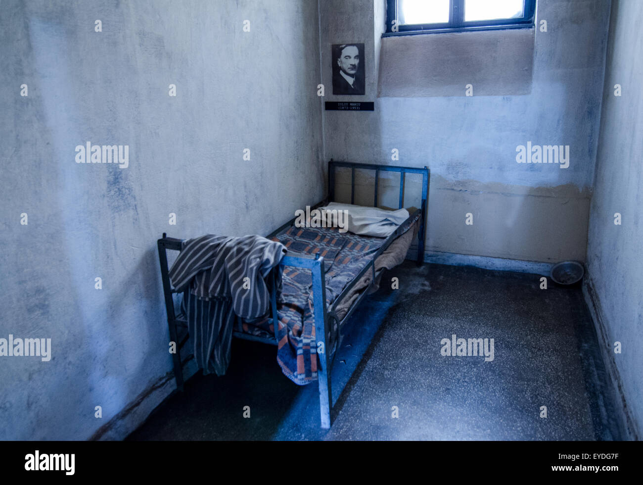 Inside a historic prison cell with basic furnishings and a small window ...