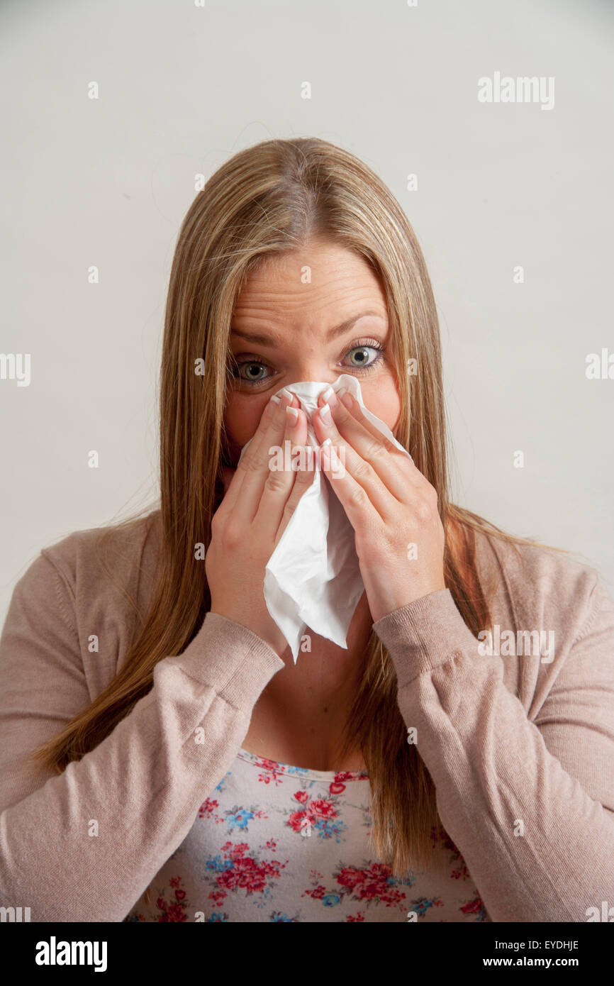 Using a handkerchief, a young adult woman blows her nose in Laguna ...