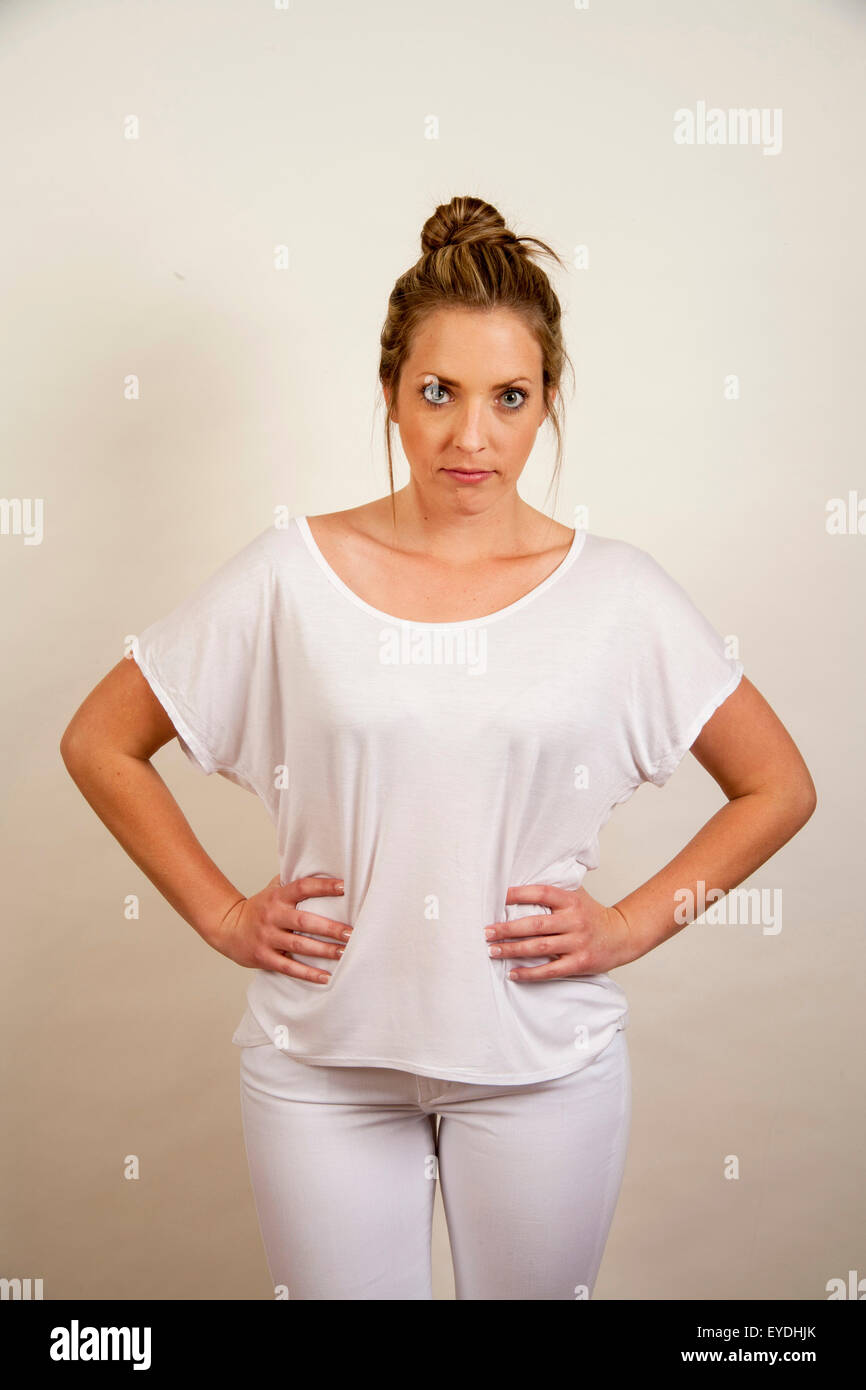 A serious young adult woman in white poses informally in a Laguna Beach ...