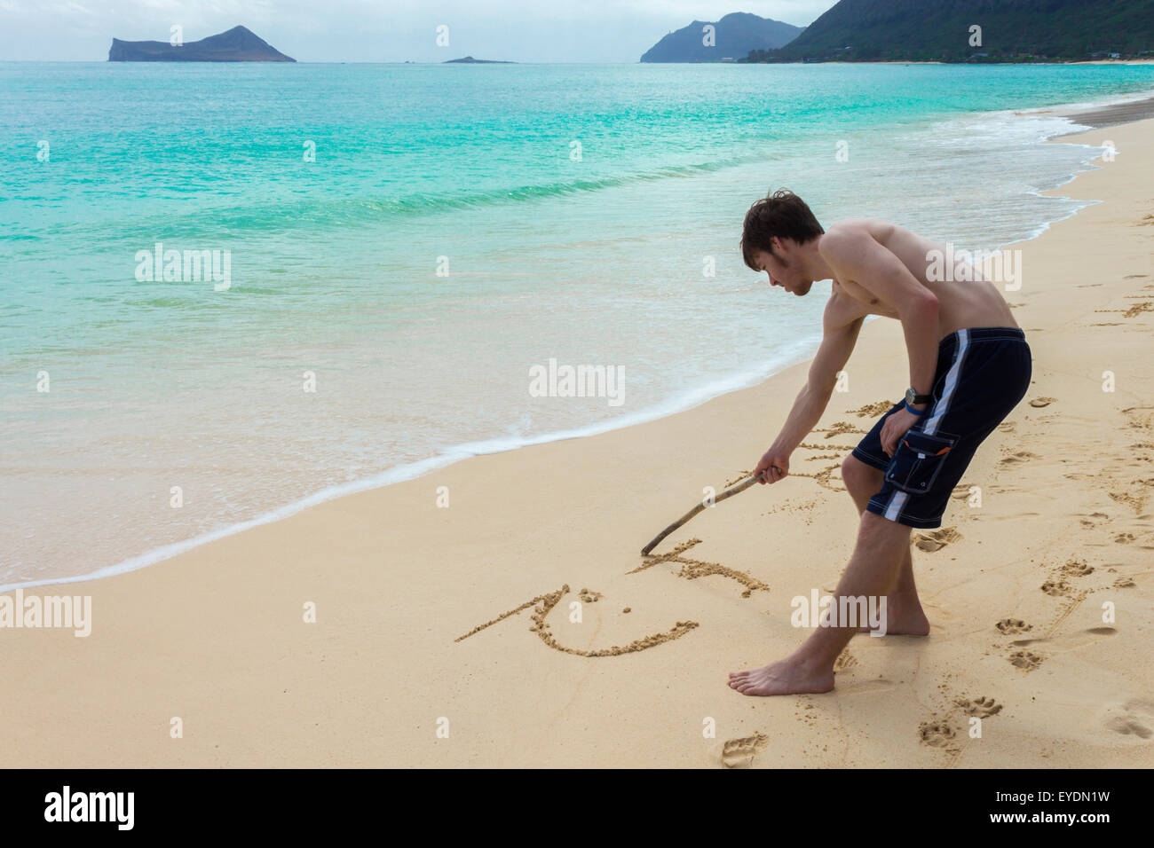 Young Man writing Japanese in sand on beautiful Hawaiian beach Stock ...