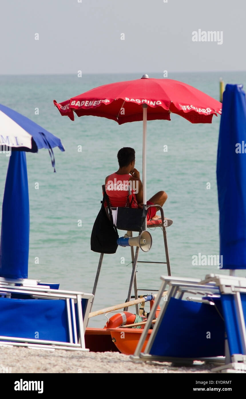 Italy, Marche, Lifeguard on watch on high chair and sun umbrella; Porto ...