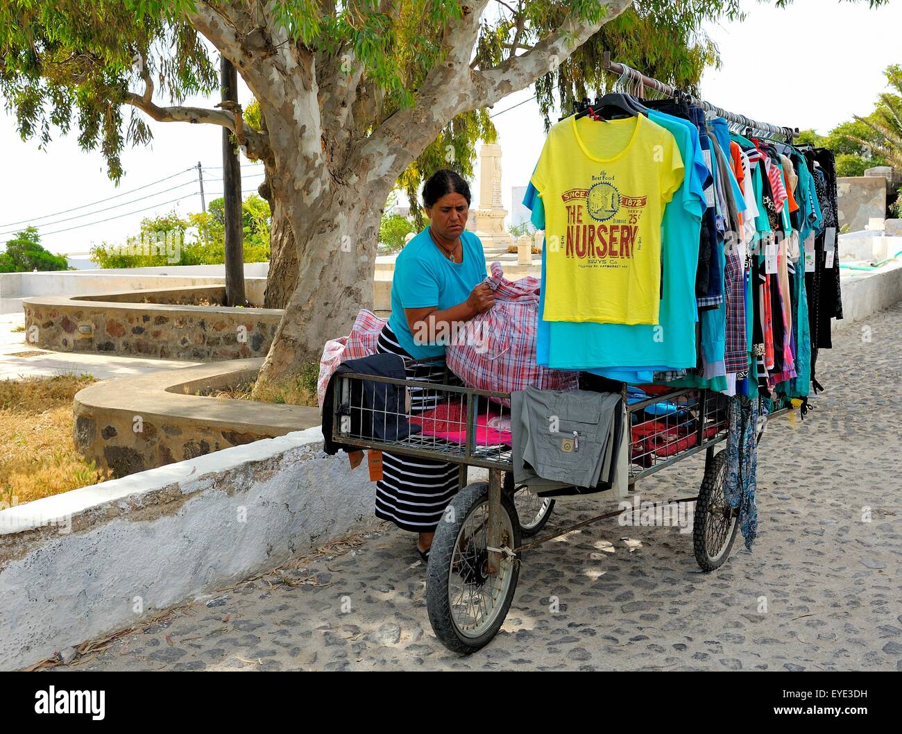 A local woman with a mobile market stall selling children's clothing ...