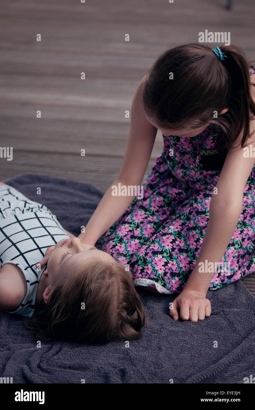 Child practising first aid CPR and checking the pulse on another child ...