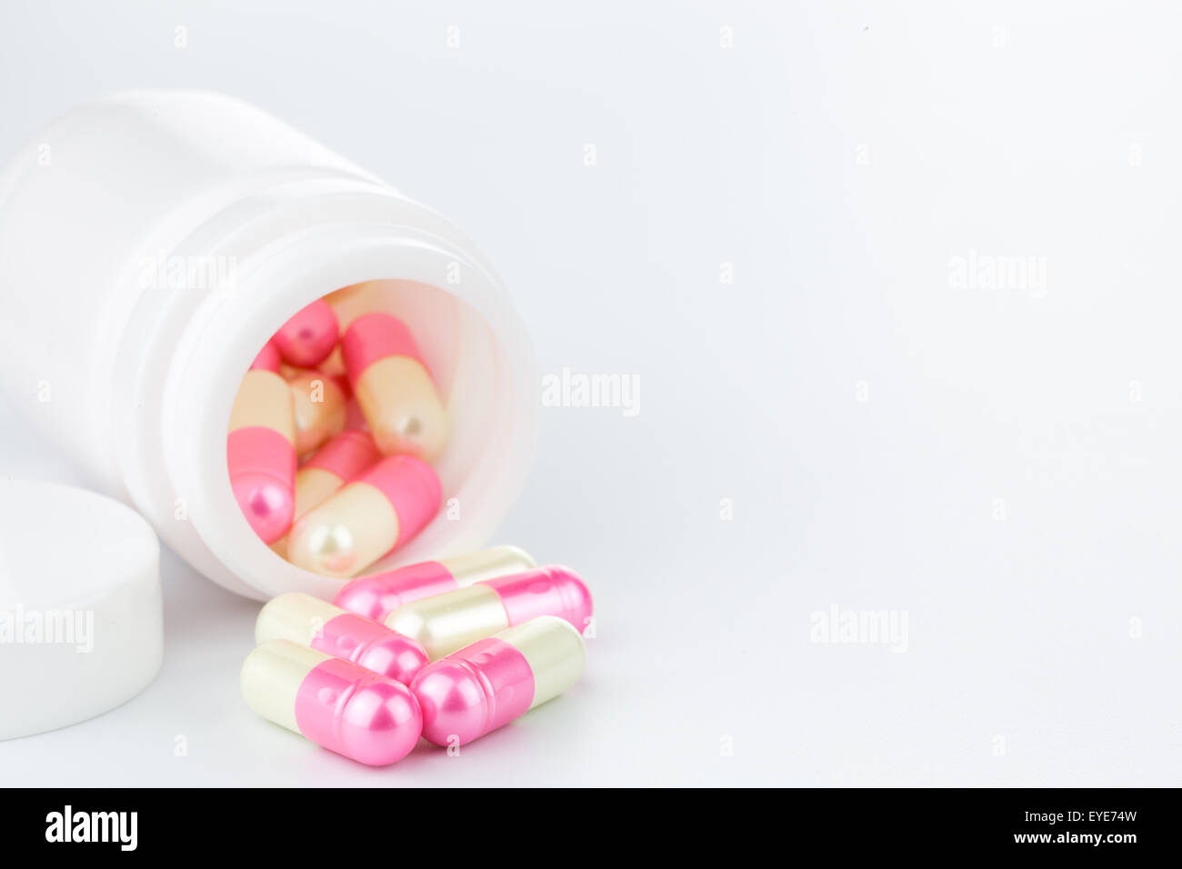 Pink and yellow pearl pills an pill bottle on white background ...