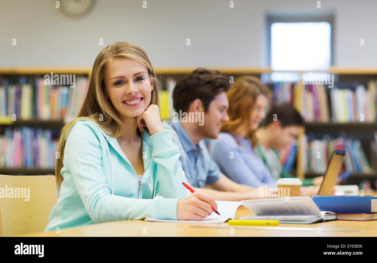 happy student girl writing to notebook in library Stock Photo - Alamy