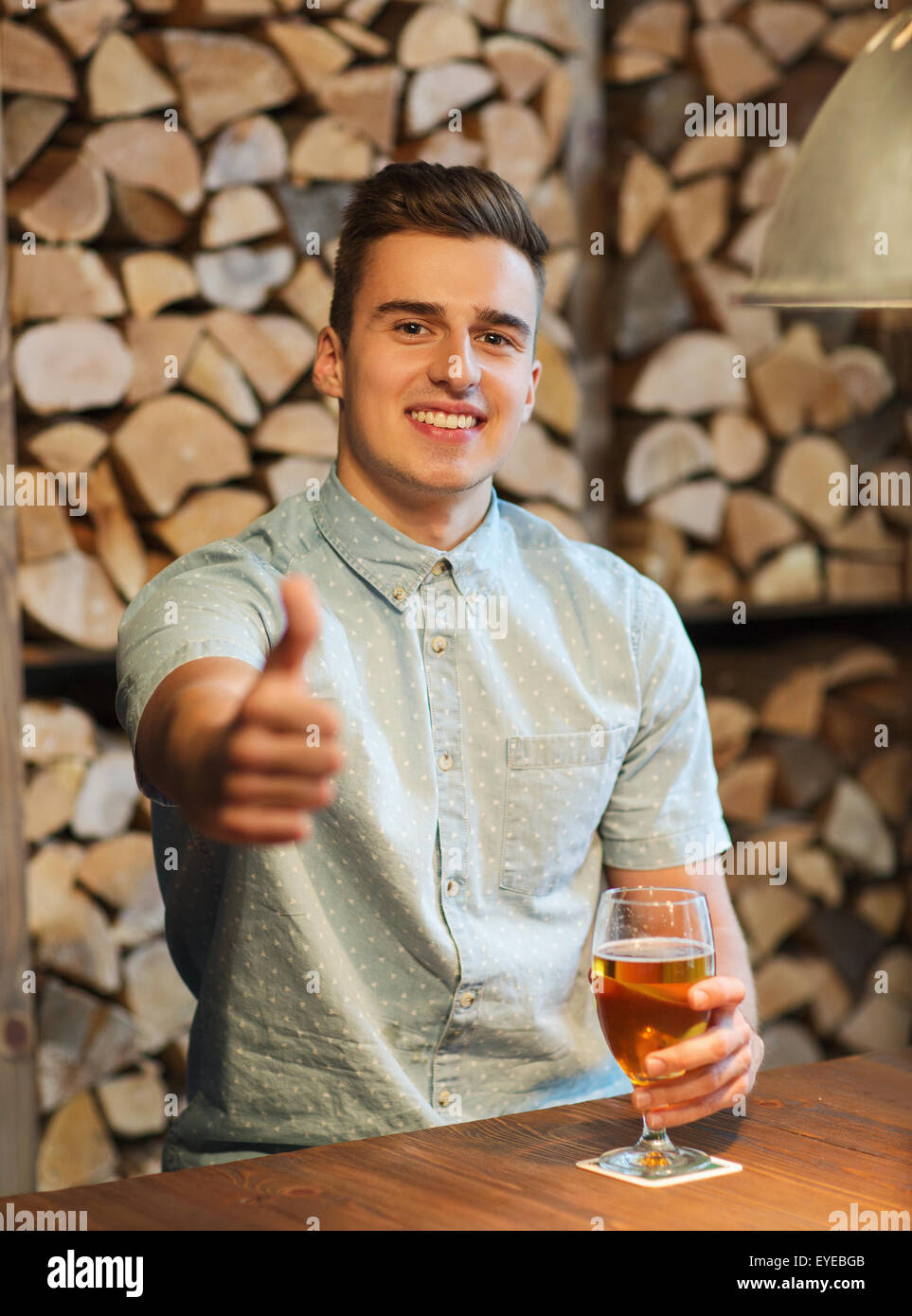 happy man with beer showing thumbs up at bar Stock Photo - Alamy