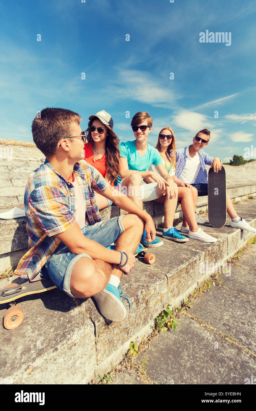 group of smiling friends sitting on city street Stock Photo - Alamy