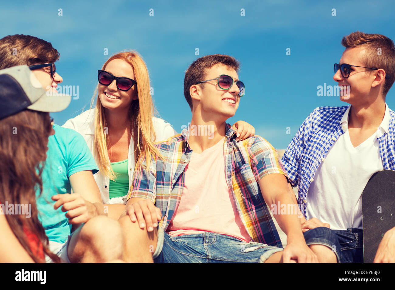 group of smiling friends sitting on city street Stock Photo - Alamy
