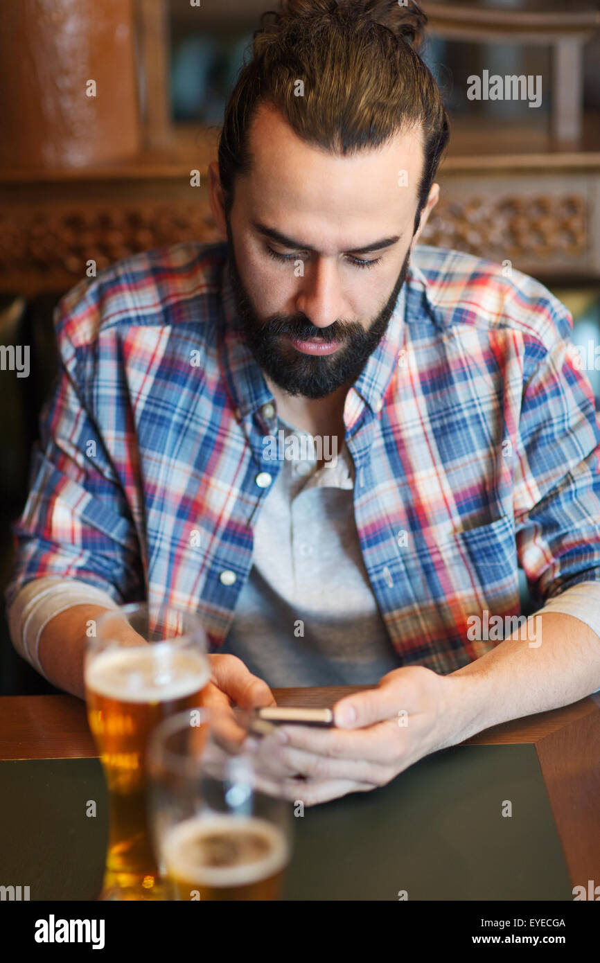 man with smartphone drinking beer at bar Stock Photo - Alamy