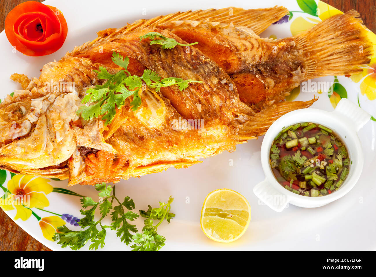 Thai fried fish and cooked on a plate with lemon and the peel of an ...