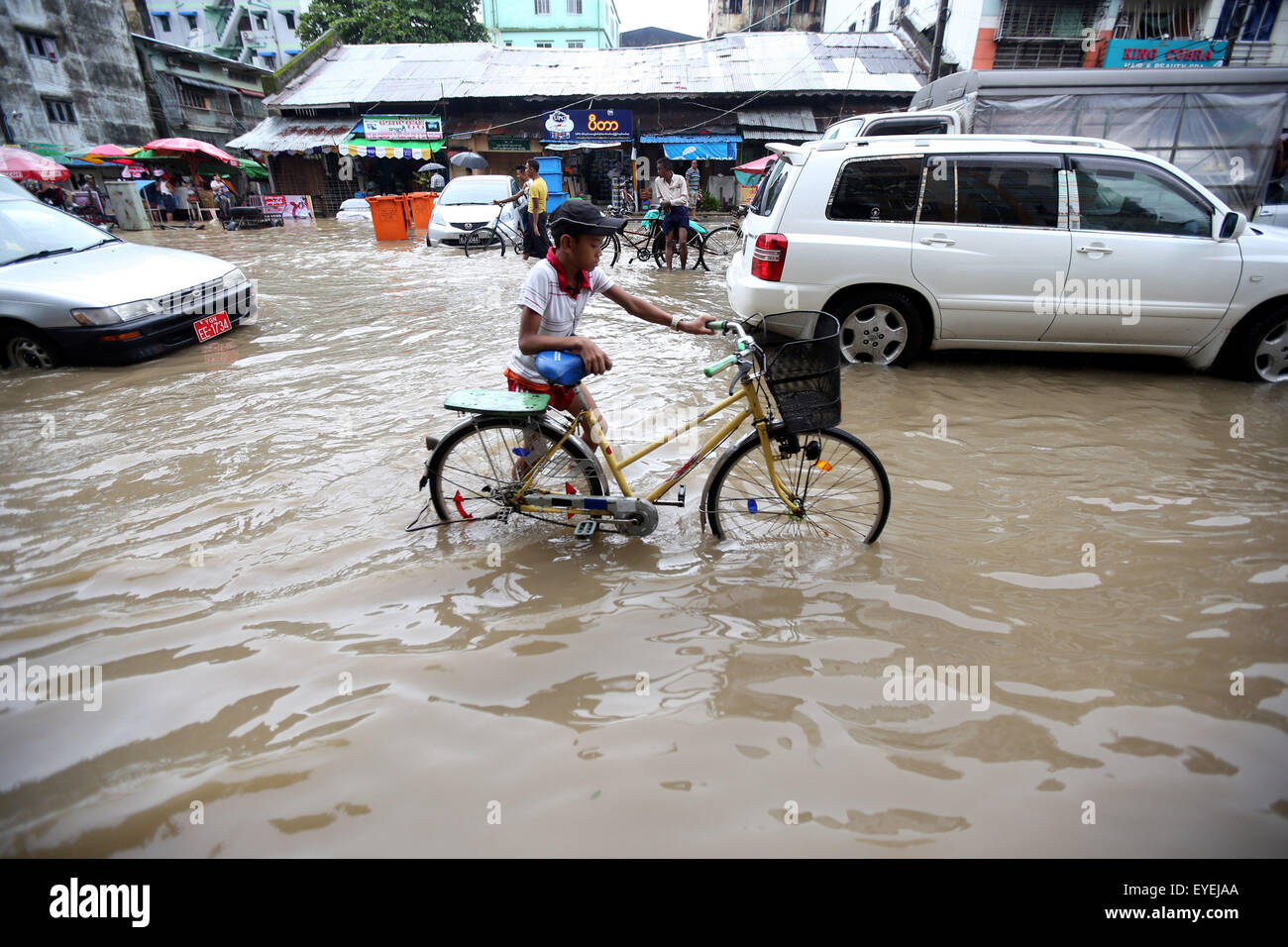 Yangon, Myanmar. 28th July, 2015. People wade through a flooded area in ...