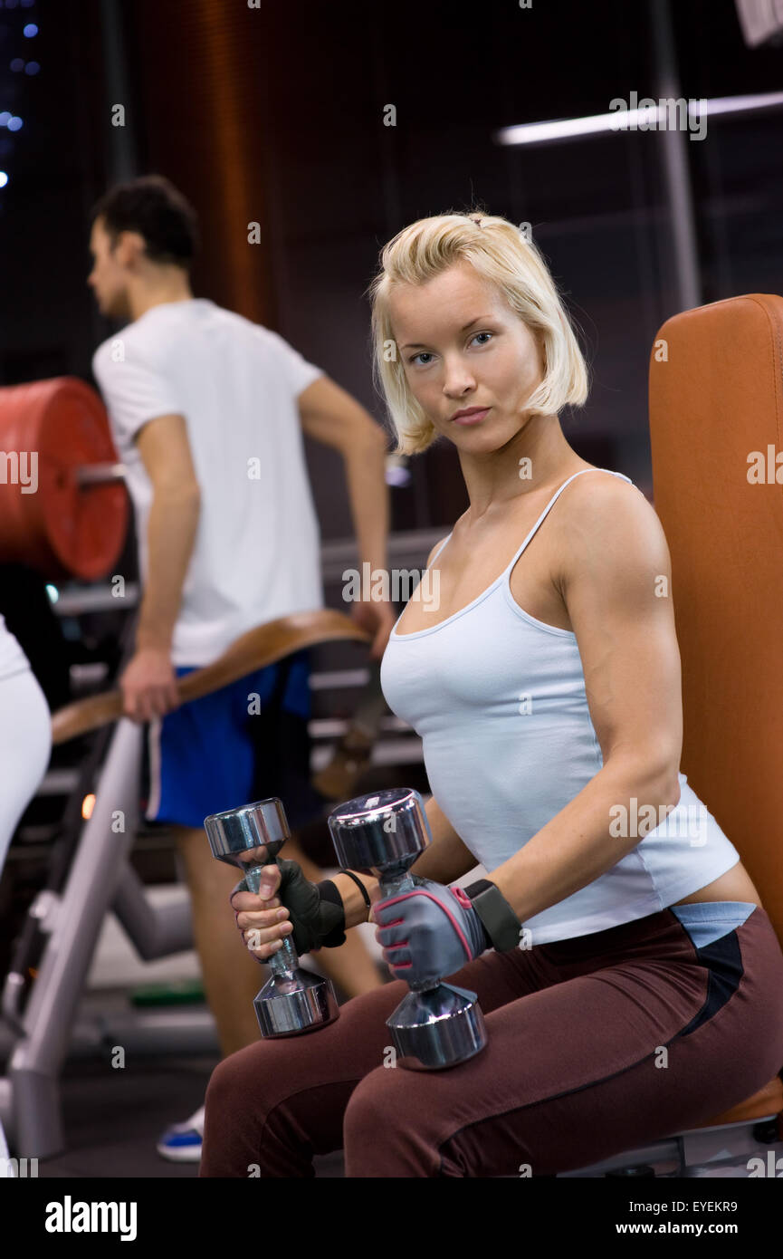 Strong beautiful woman lifting heavy dumbbells Stock Photo - Alamy