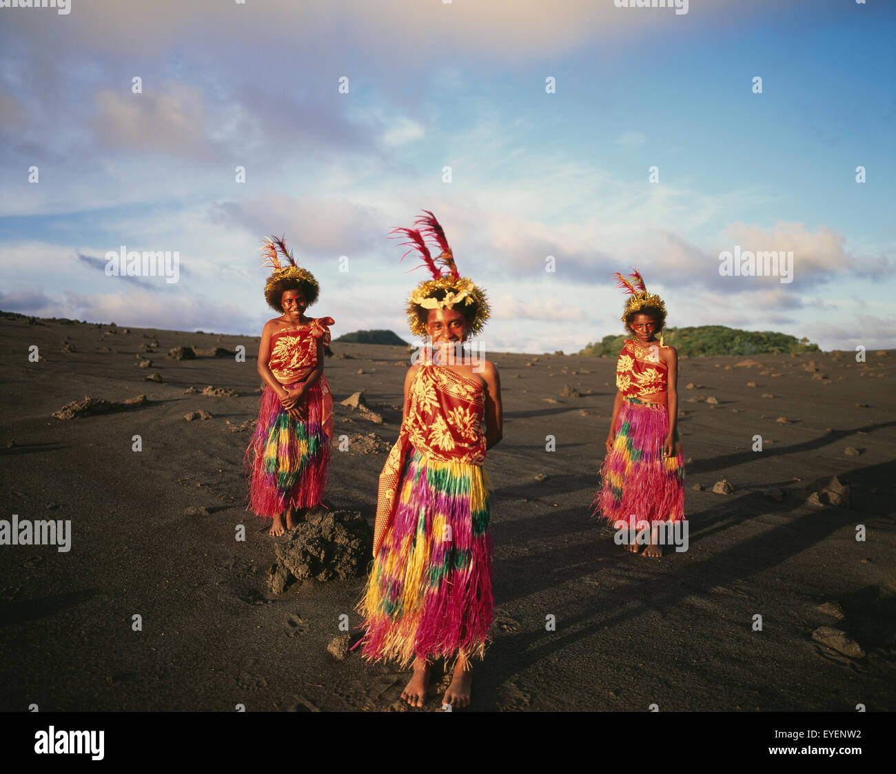 Three young woman standing on the lava fields of Yasur Volcano; Tanna ...