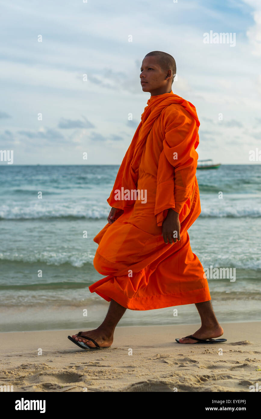 A monk walks on the sand of Serendipity Beach; Sihanoukville, Cambodia ...