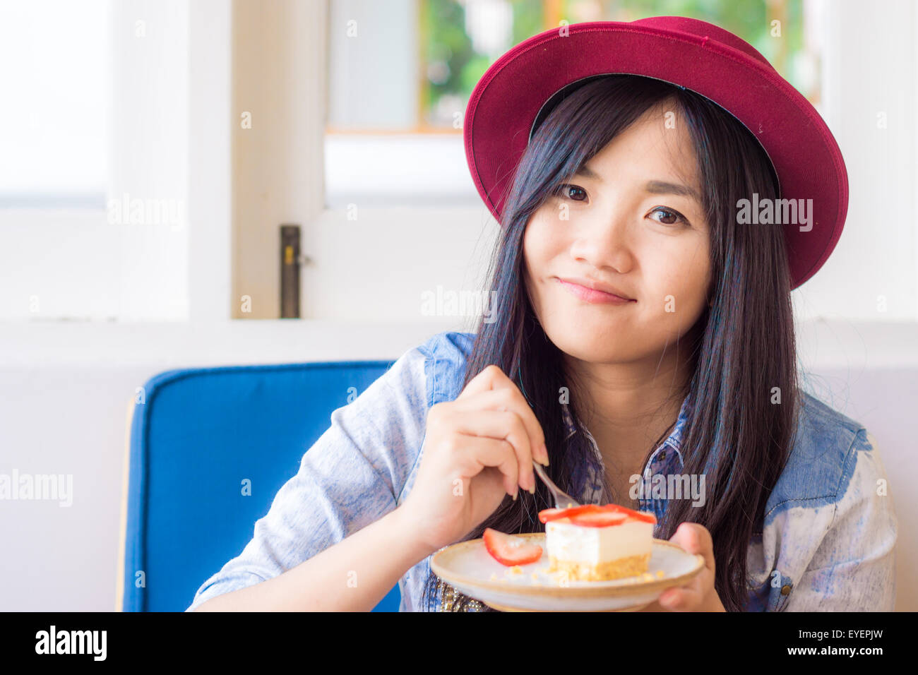 Smiling young asian woman eating cake in bakery shop, Smiling and look ...