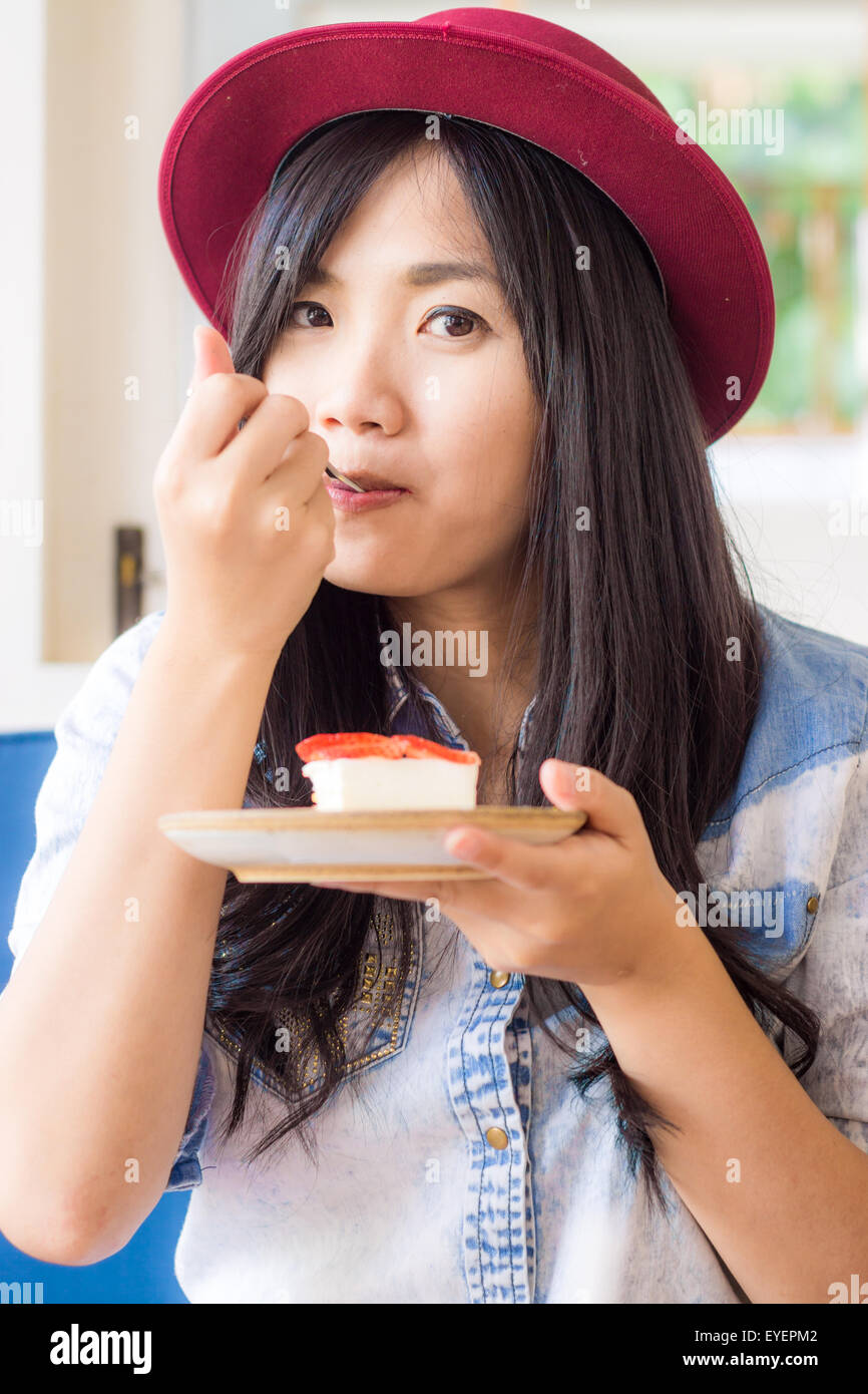 Smiling young asian woman eating cake in bakery shop, Smiling and look ...