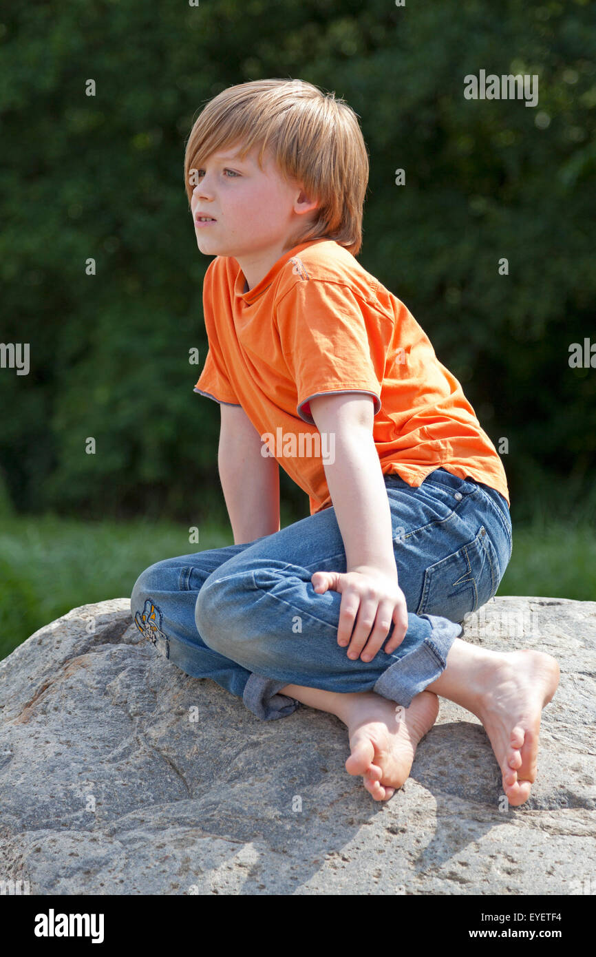 portrait of a young boy sitting on a rock Stock Photo - Alamy