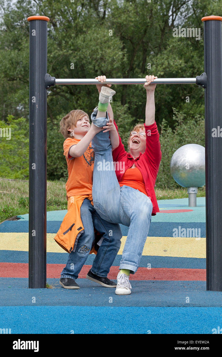 young son helping his mother climb a high bar on a playground Stock ...