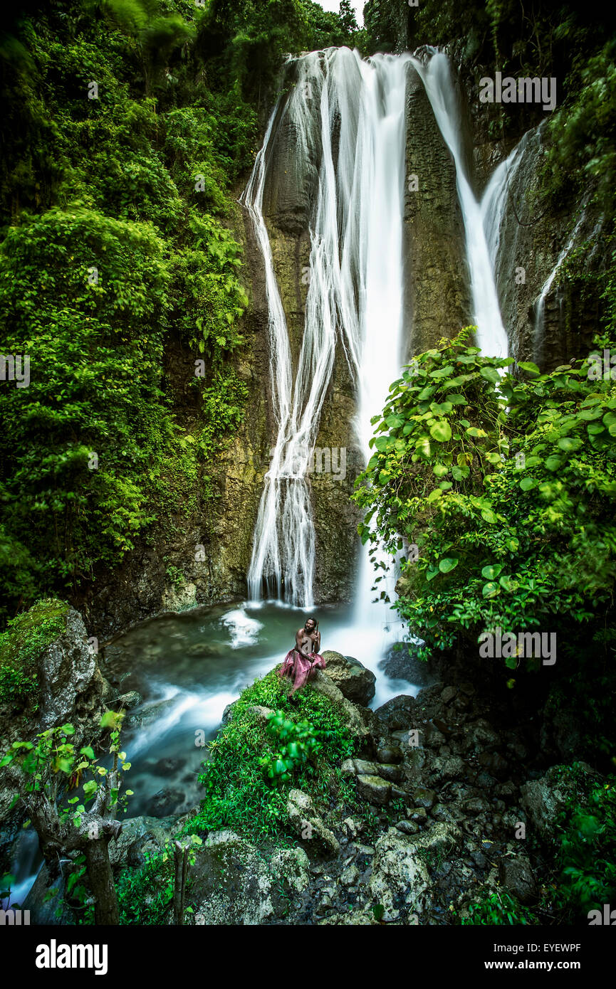 A waterfall on Tanna Island with a man in traditional costume in the ...