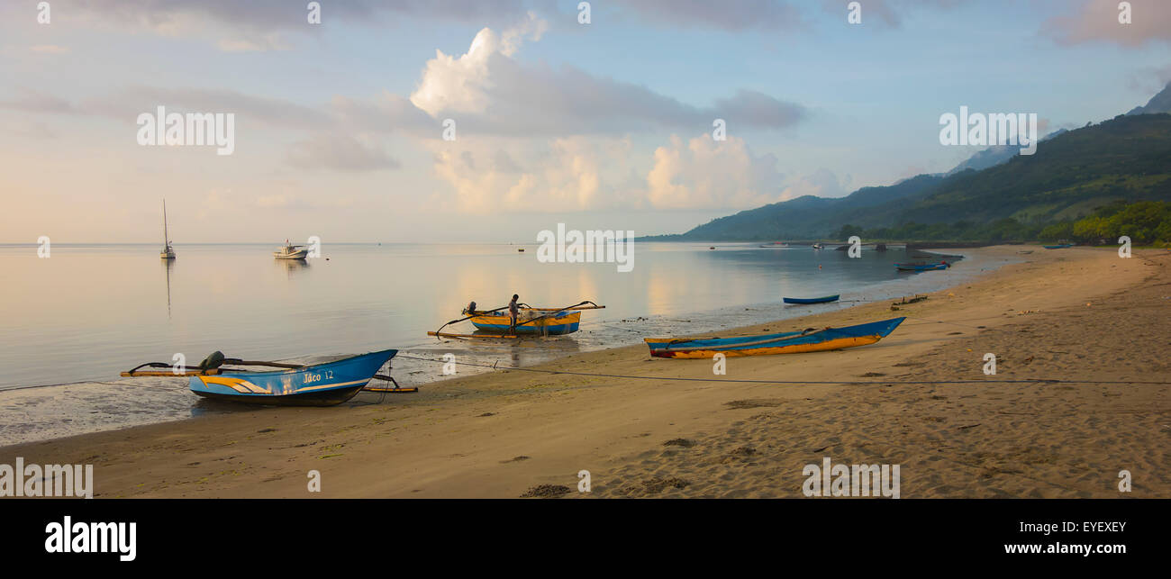 Tranquil ocean at sunrise with boats on the beach; Atauro Island, Timor ...