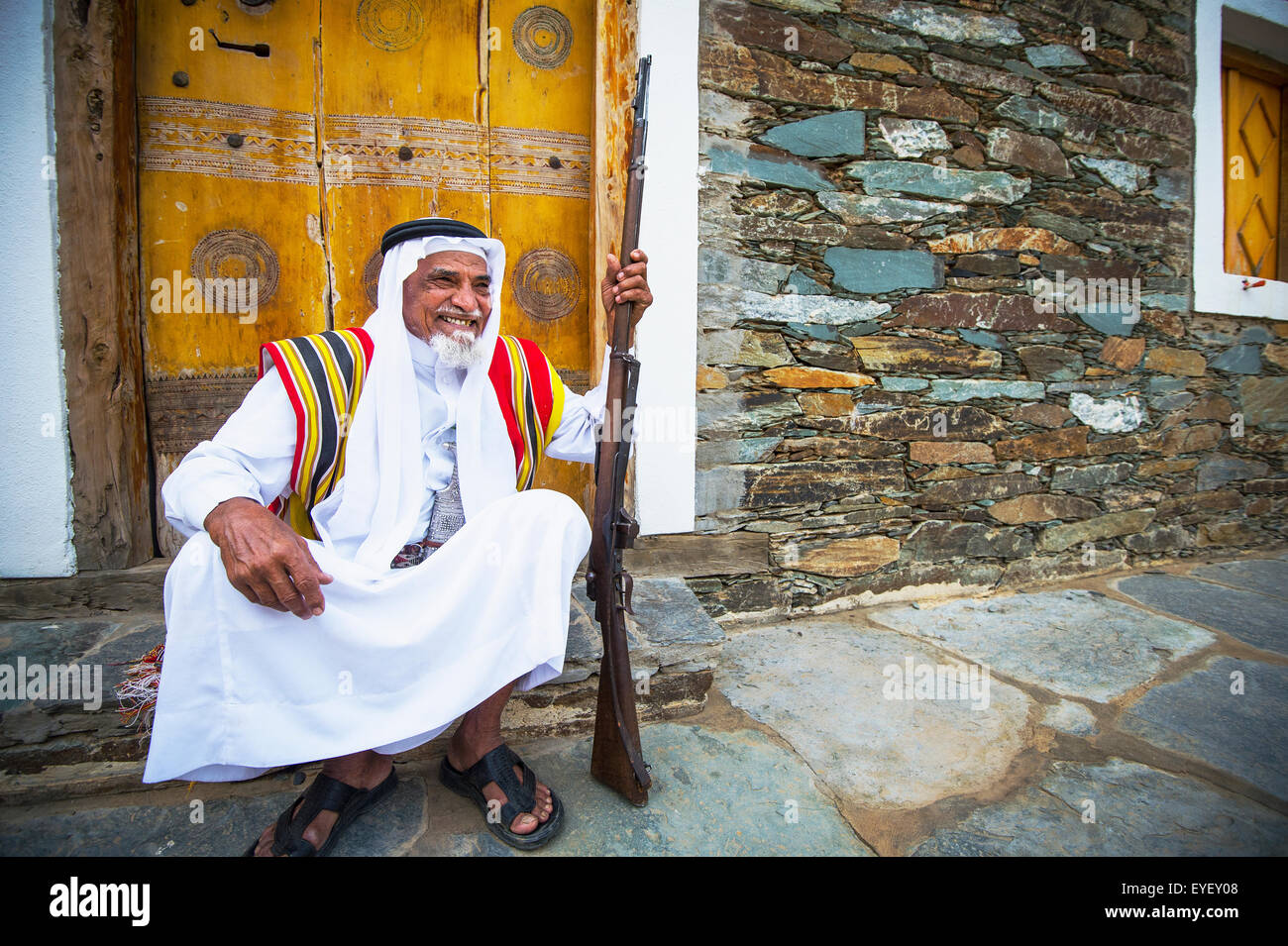 Elderly man and musket relaxing, near Rijal Alma village; Asir Province ...