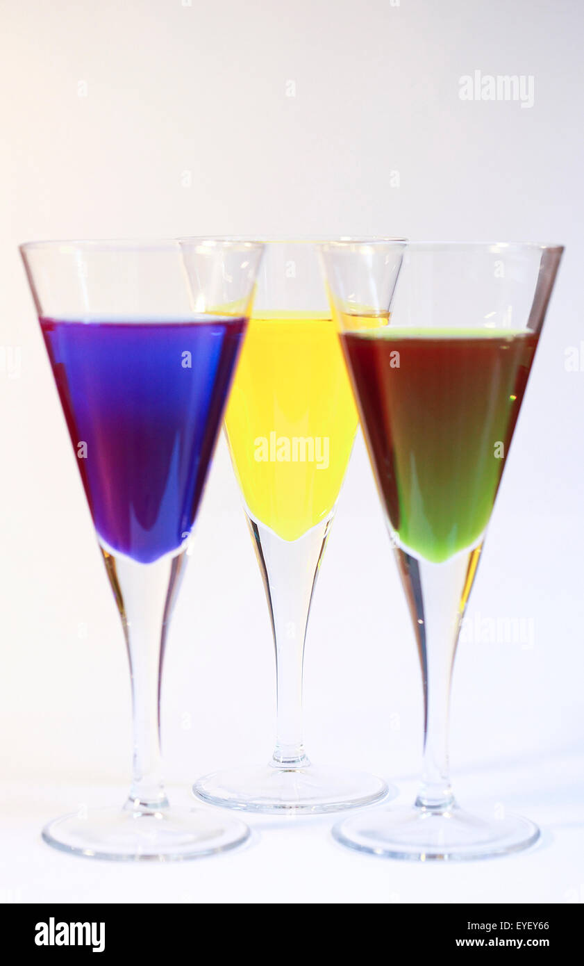 Three cocktails of bright colored alcohol against a white background ...