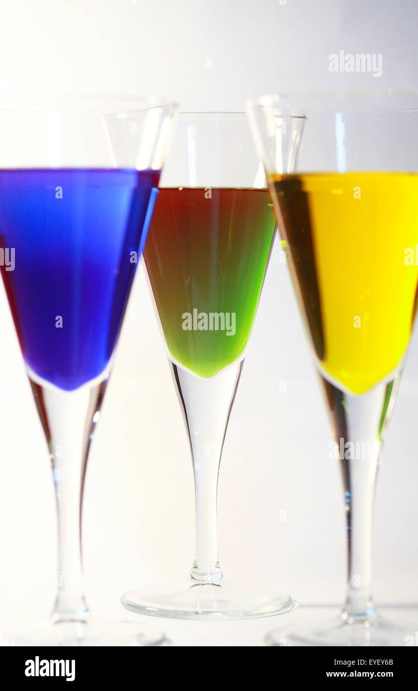 Three cocktails of bright colored alcohol against a white background ...
