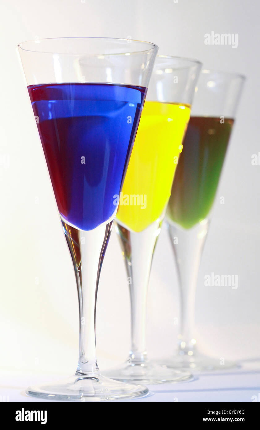 Three cocktails of bright colored alcohol against a white background ...
