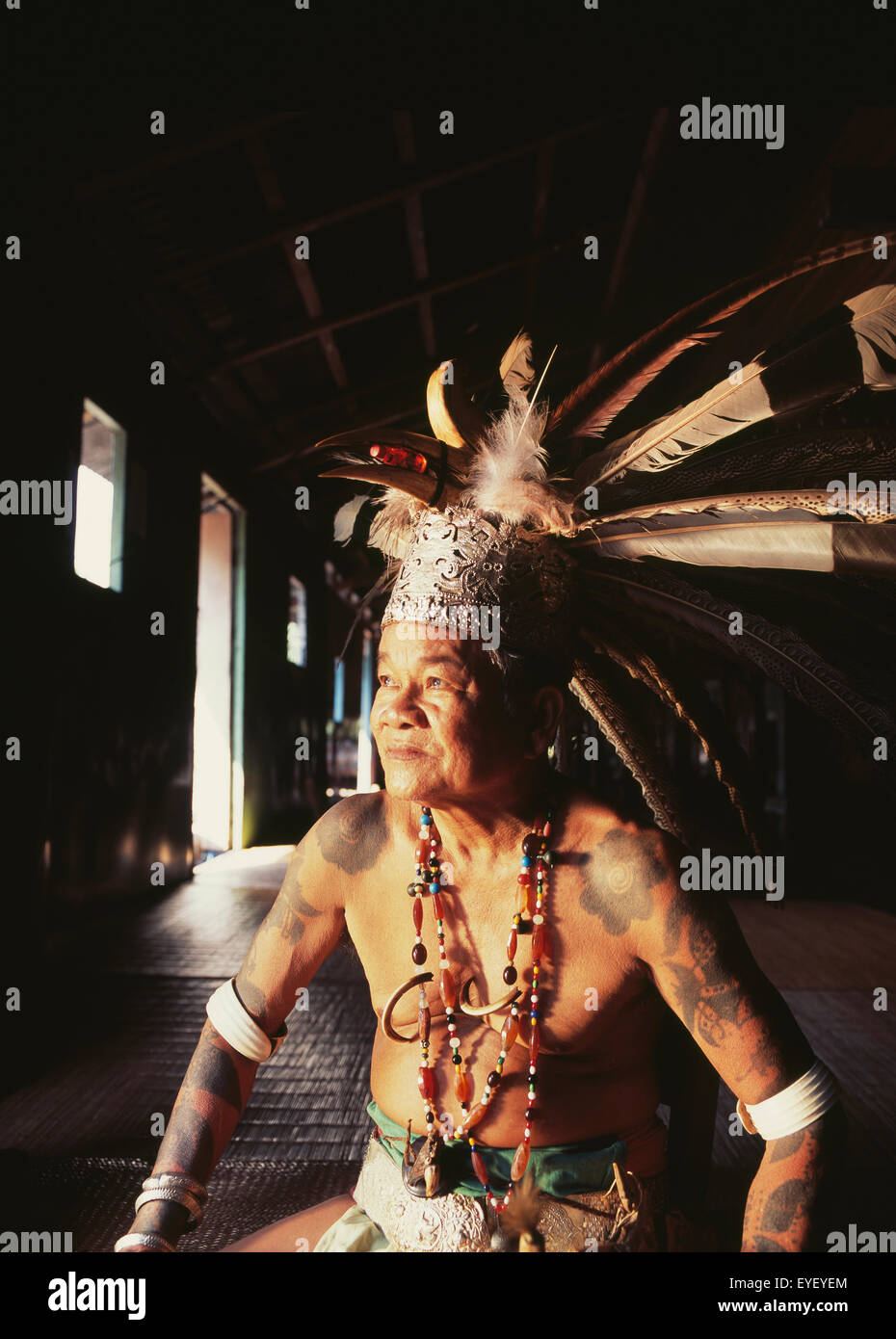 Village chief sitting in a Long House in traditional dress; Sarawak ...