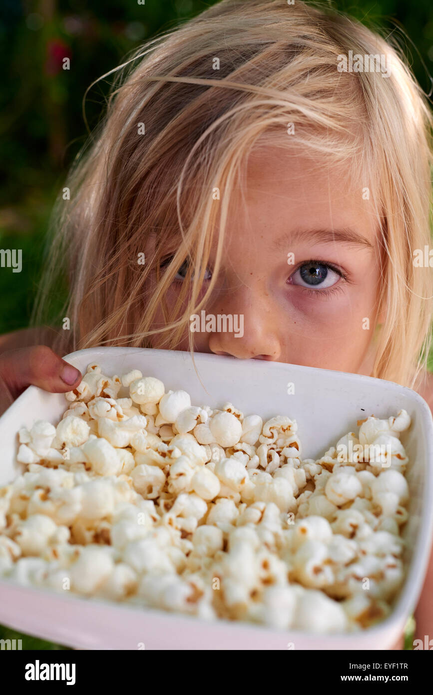 Child blond girl eating popcorn outside Stock Photo - Alamy