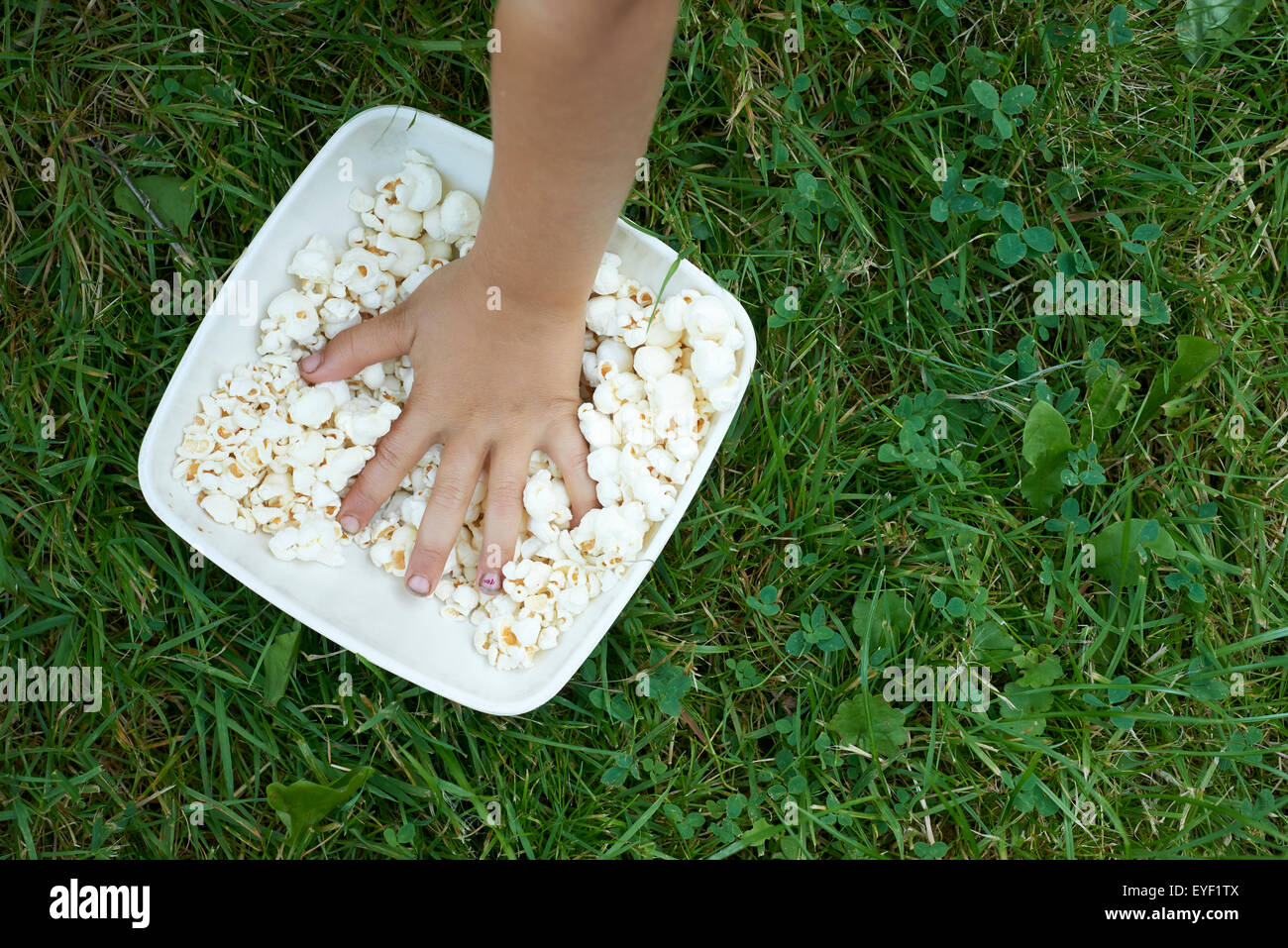 Child blond girl eating popcorn outside Stock Photo - Alamy