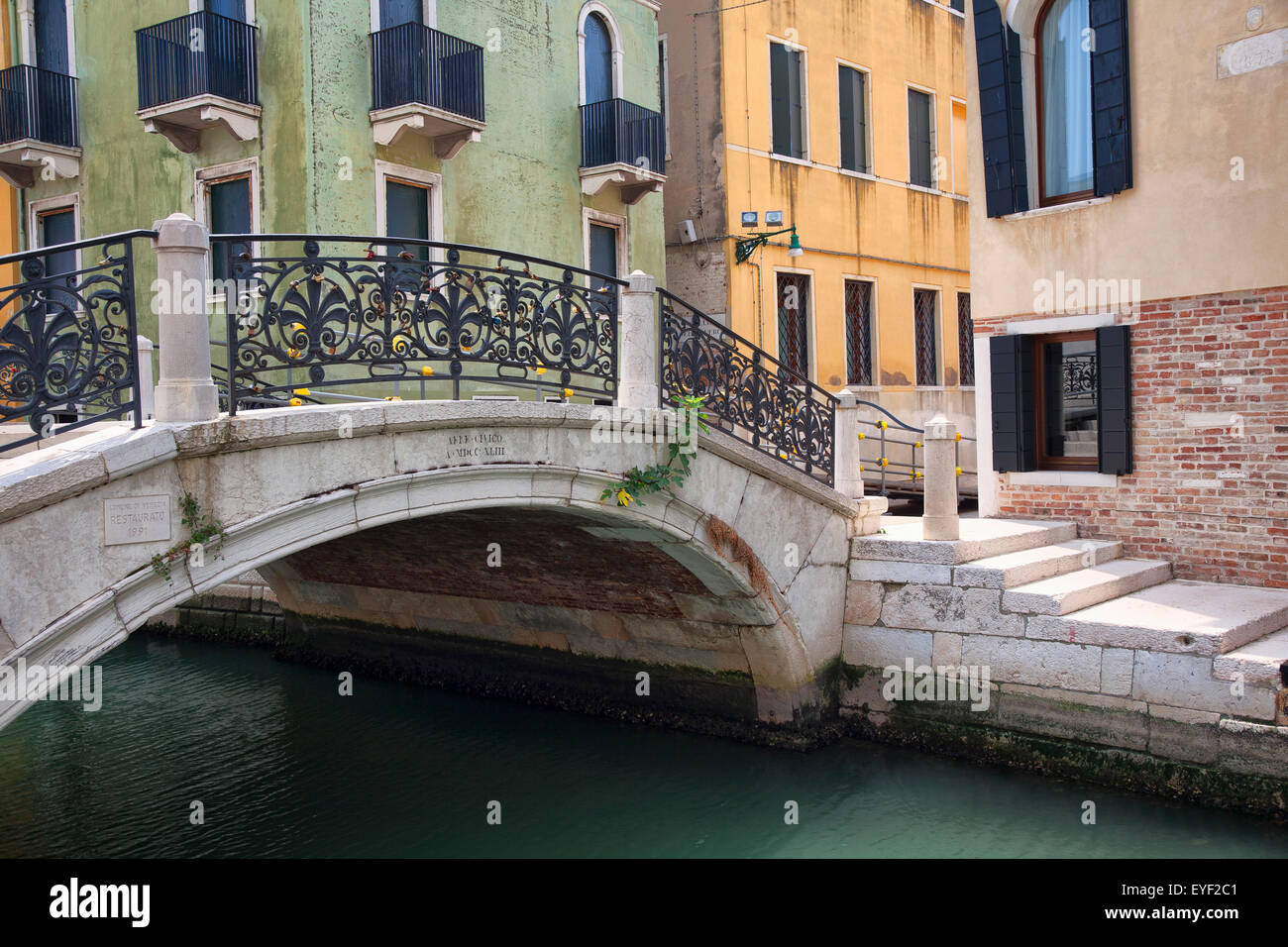 A quaint bridge over a small canal with colourful buildings; Venice ...