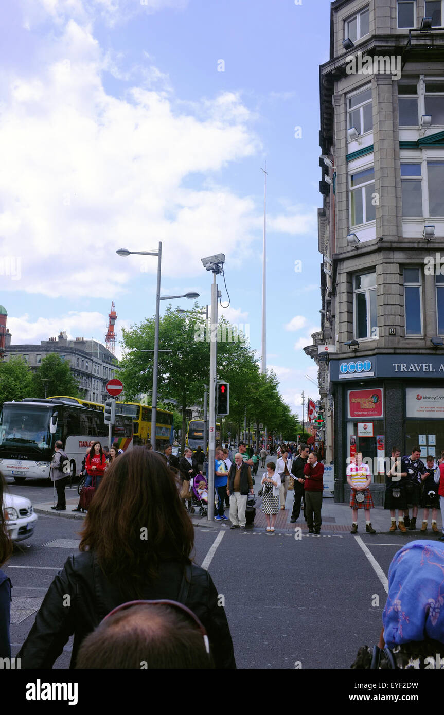 Pedestrians cross the road to walk towards The Spire of Dublin on O ...