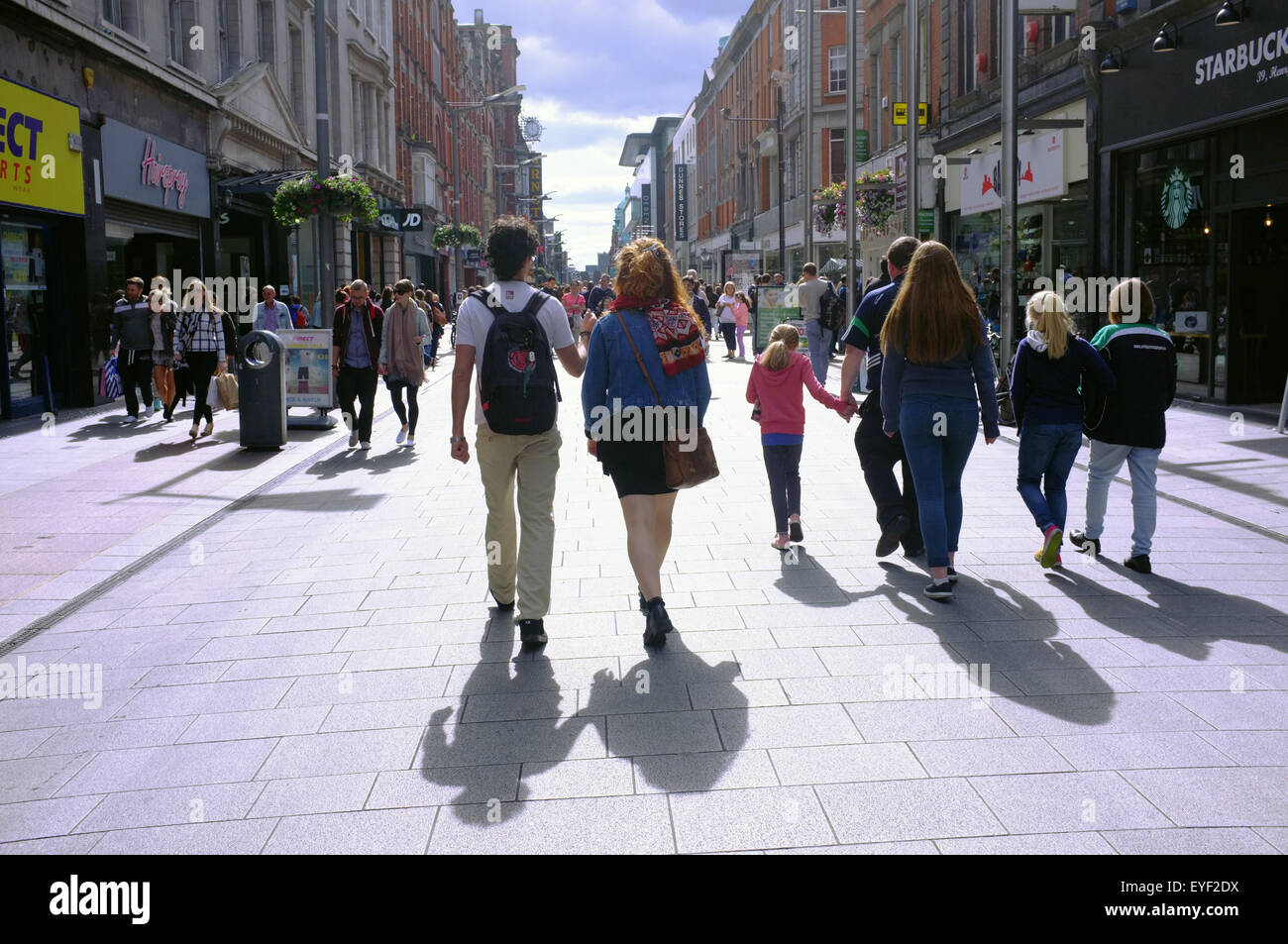 Pedestrians walking towards the sun down a street in Dublin Stock Photo ...