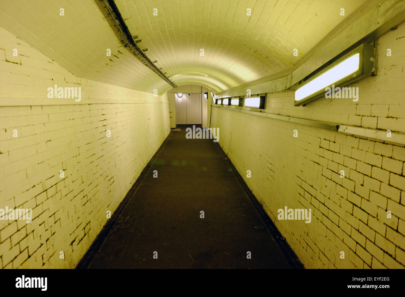 A passenger tunnel running underground between two railway platforms ...