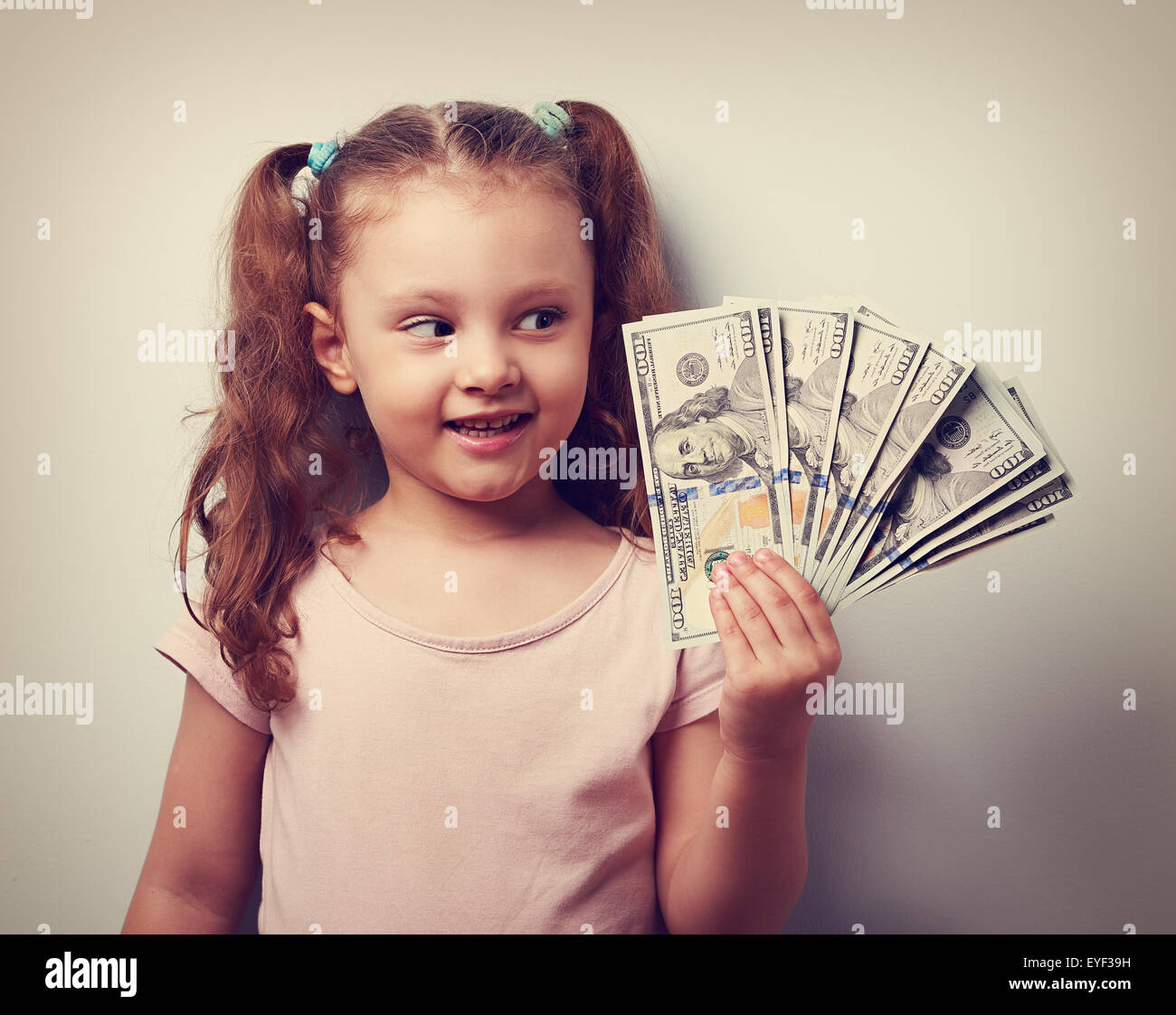 Happy thinking kid girl looking on the money in the hand and joy ...