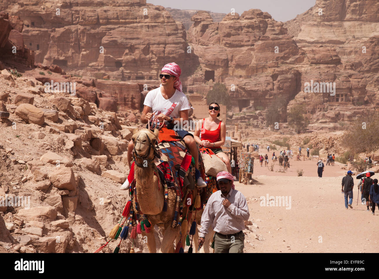 Tourists on camels riding along the colonnaded street; Petra, Jordan ...