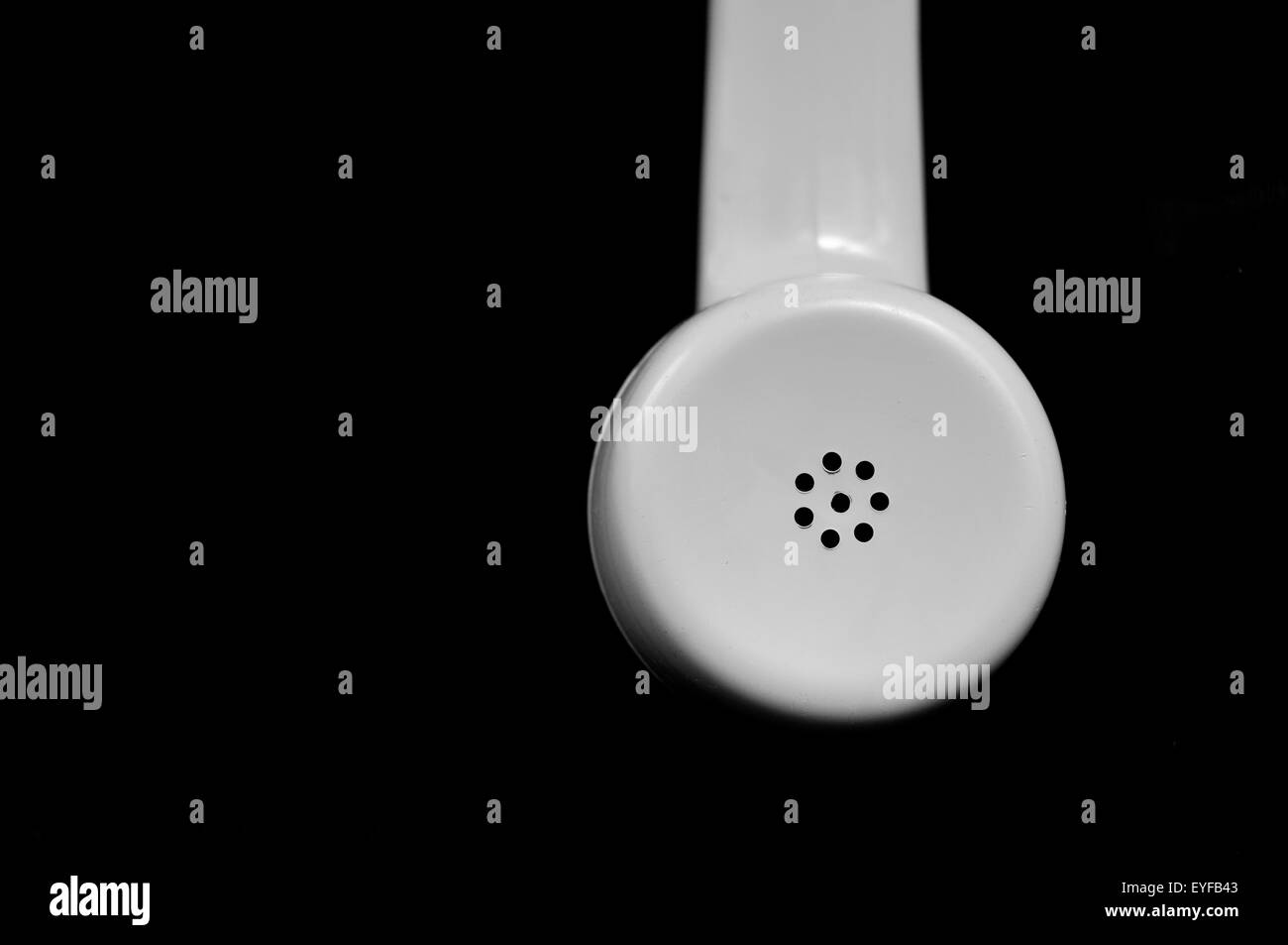 closeup of the handset of a retro gray telephone on a black background ...