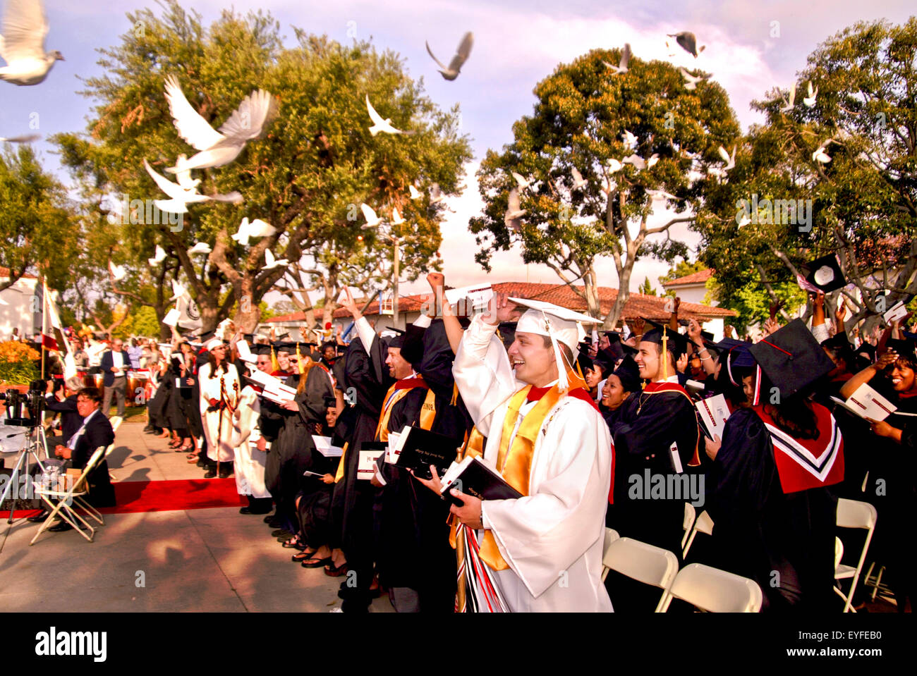 Happy community college graduates wave as doves are released at ...