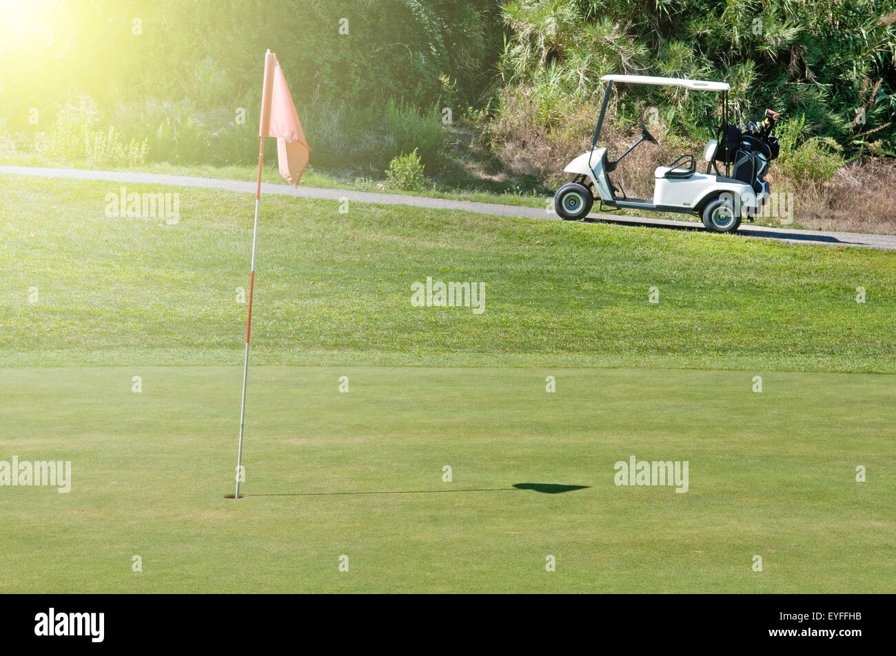 Golf cart next to a hole on a golf course Stock Photo - Alamy